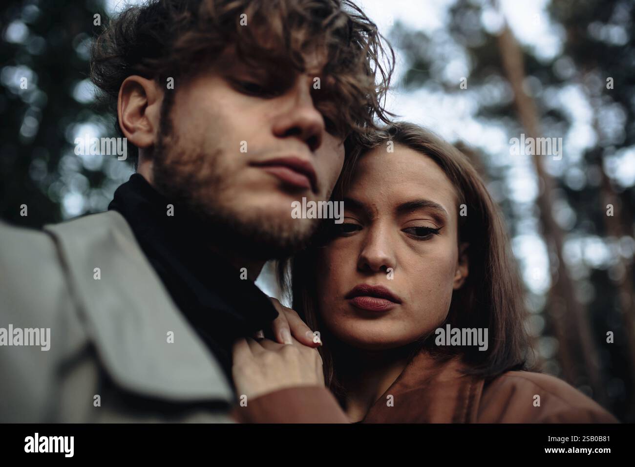 Introspective close-up of a couple in soft light within a forest ...