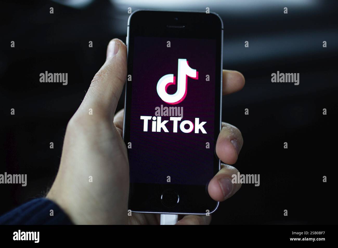 Hand gripping a smartphone with the TikTok app logo visible on screen ...