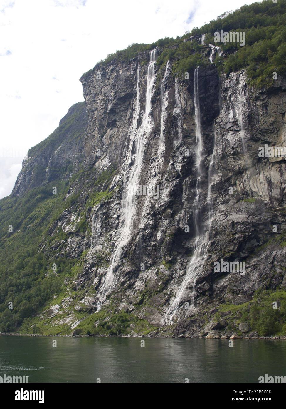 Several waterfalls flow dramatically over steep cliffs into a fjord ...