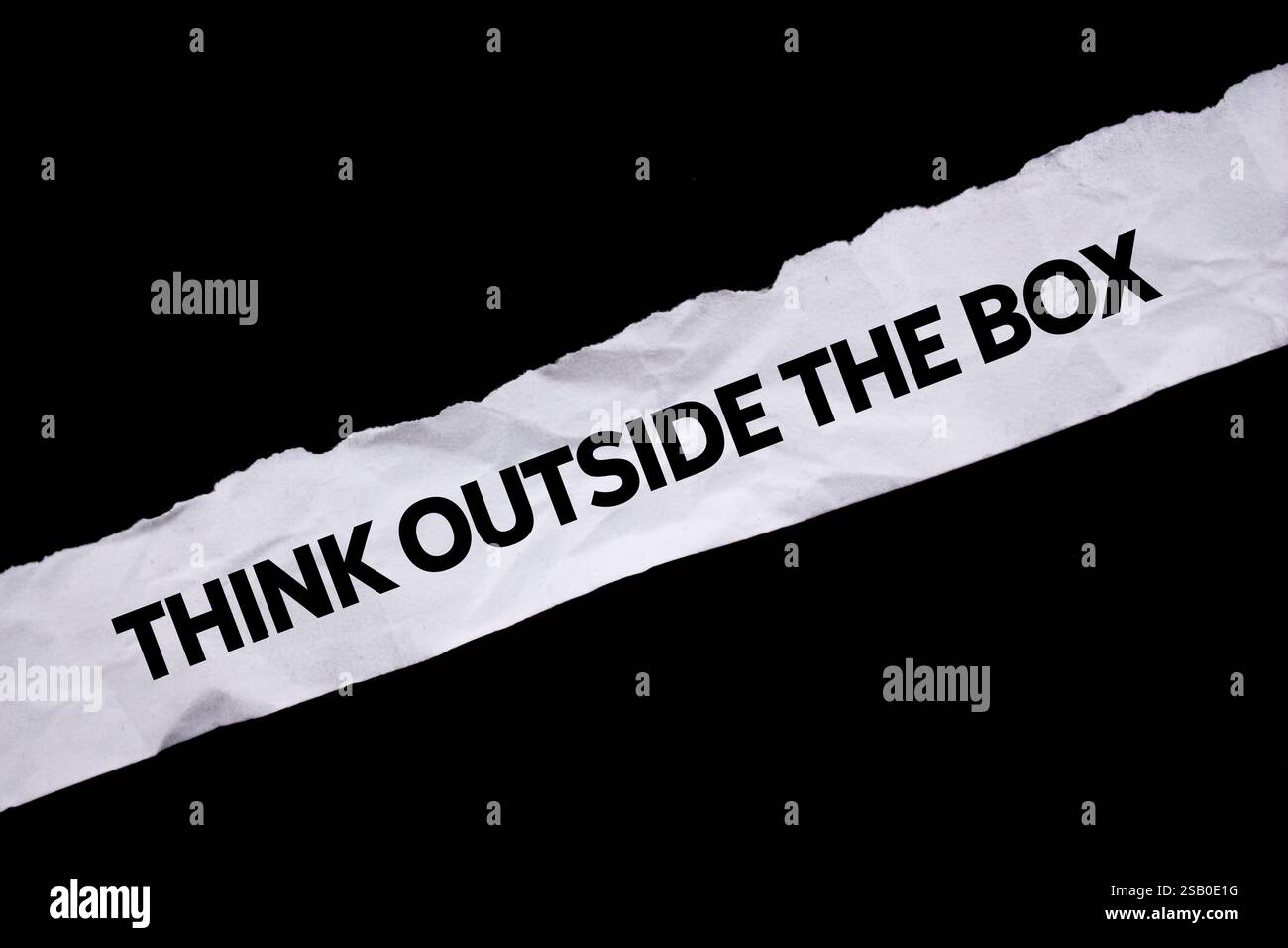 Think outside the box message written on ripped torn white paper on black background. Conceptual ...