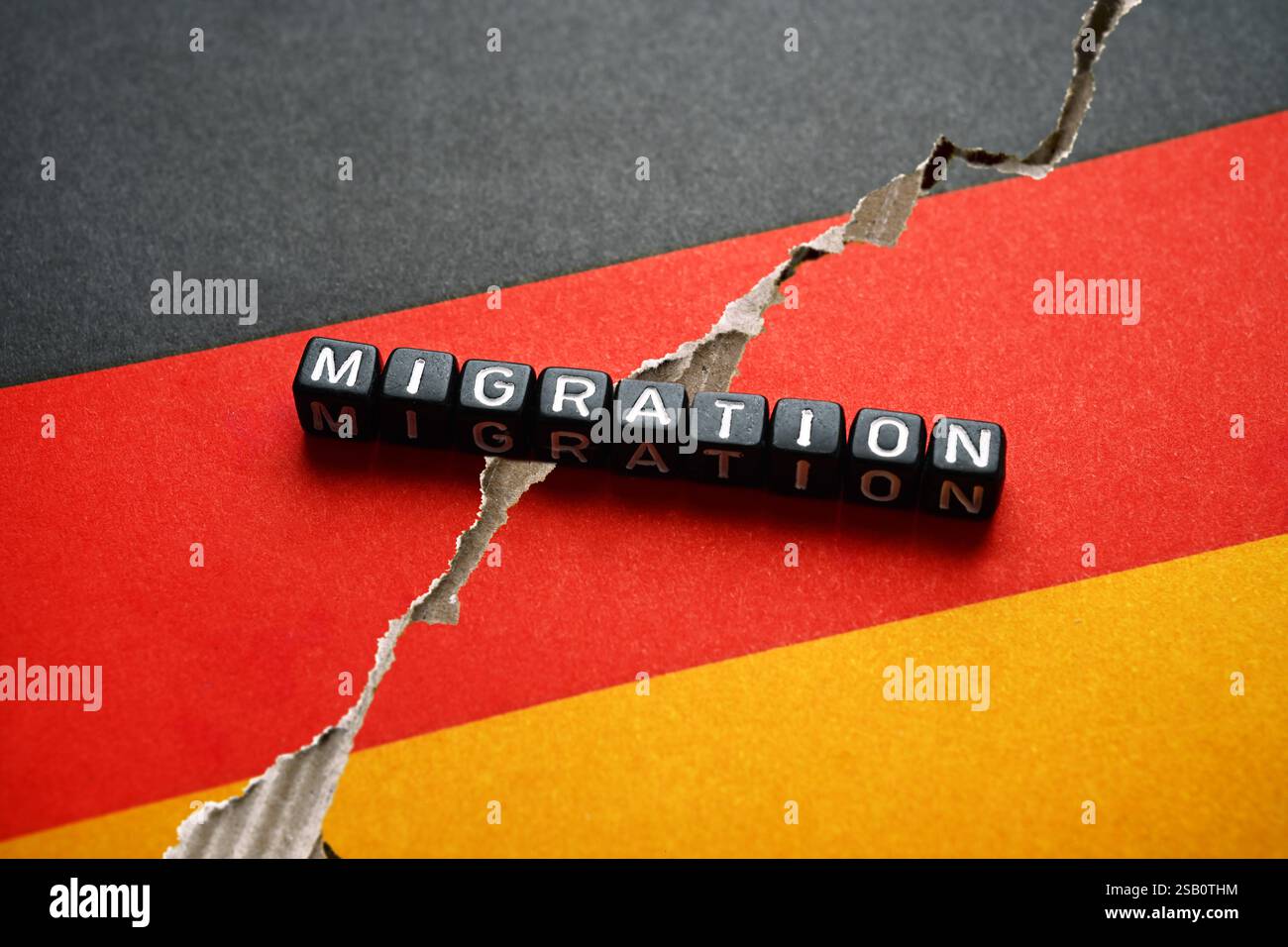 FOTOMONTAGE, Schriftzug Migration auf Deutschlandfahne mit Riss ...