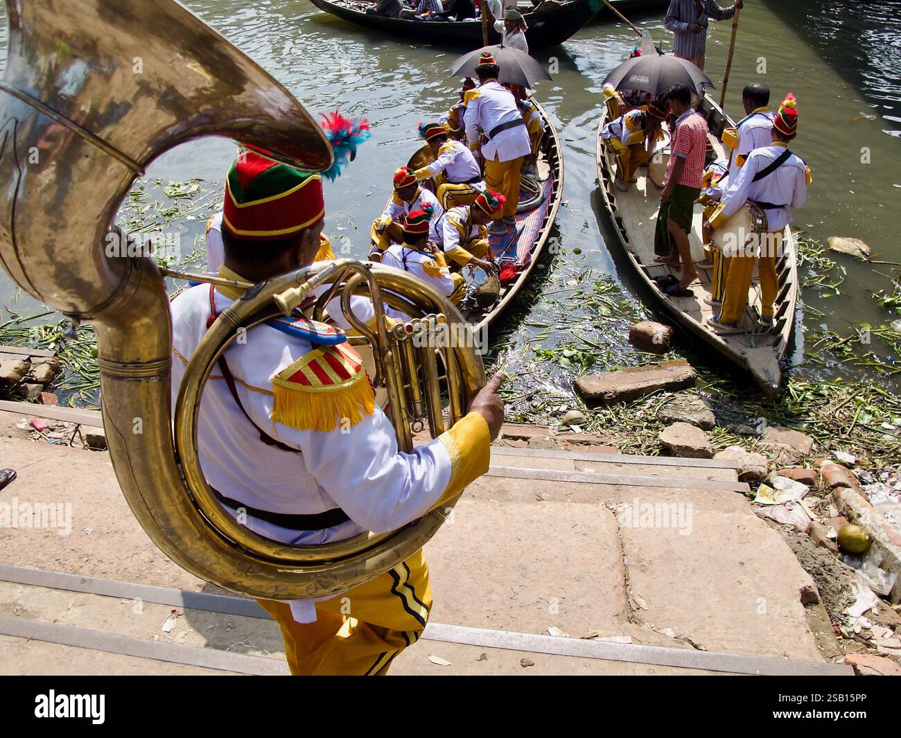 A marching band in colourful uniforms boards wooden boats to cross the Buriganga River, a key ...