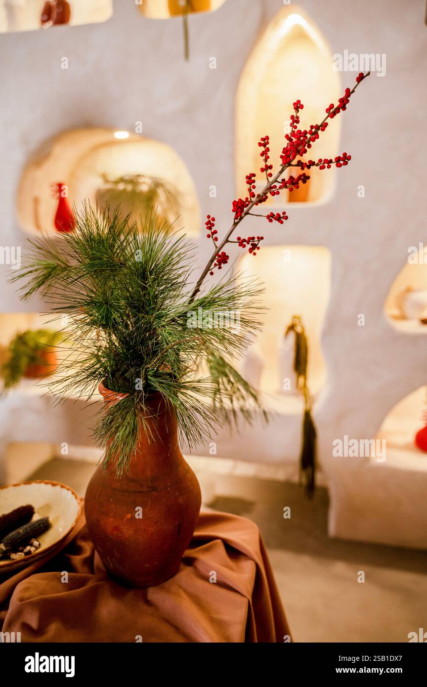 Still life with a clay pot of an old design with a pine branch and red ...