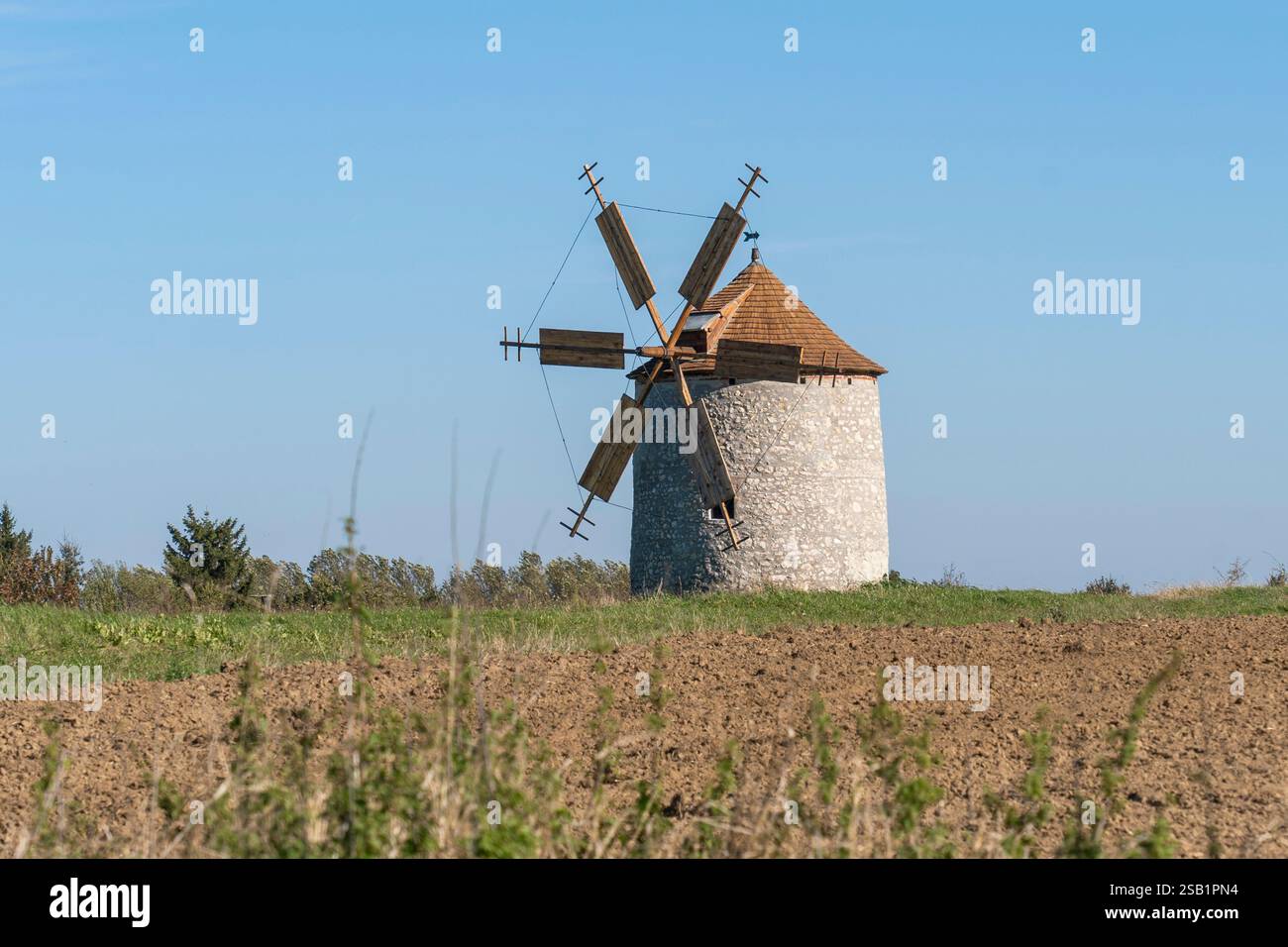 Rustic stone windmill in a grassy field Stock Photo - Alamy