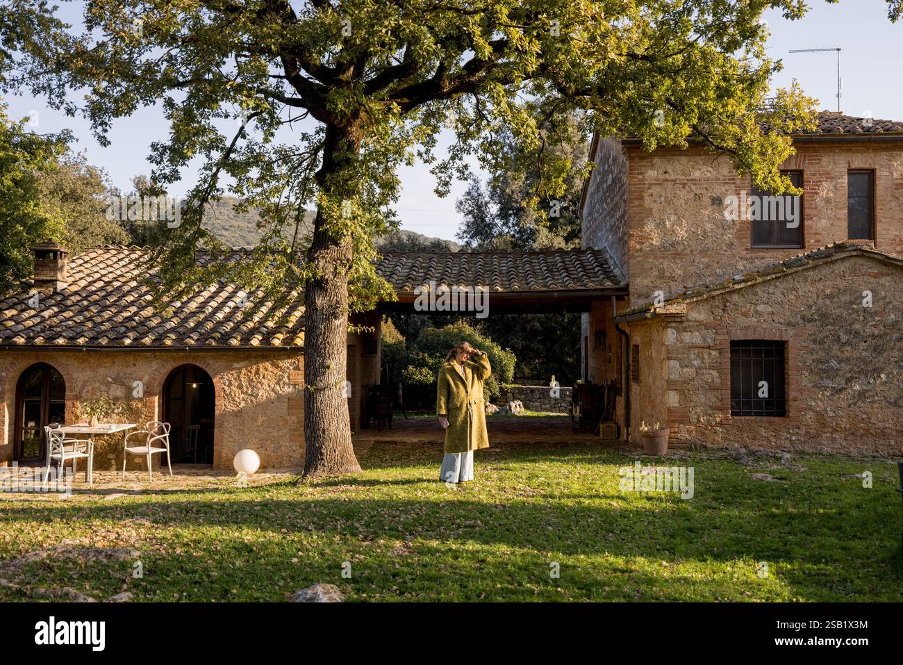 A peaceful courtyard scene featuring a woman in a green coat standing ...