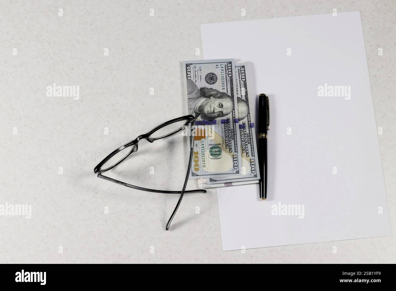 A sheet of paper, glasses, a writing pen, American dollars on the table ...