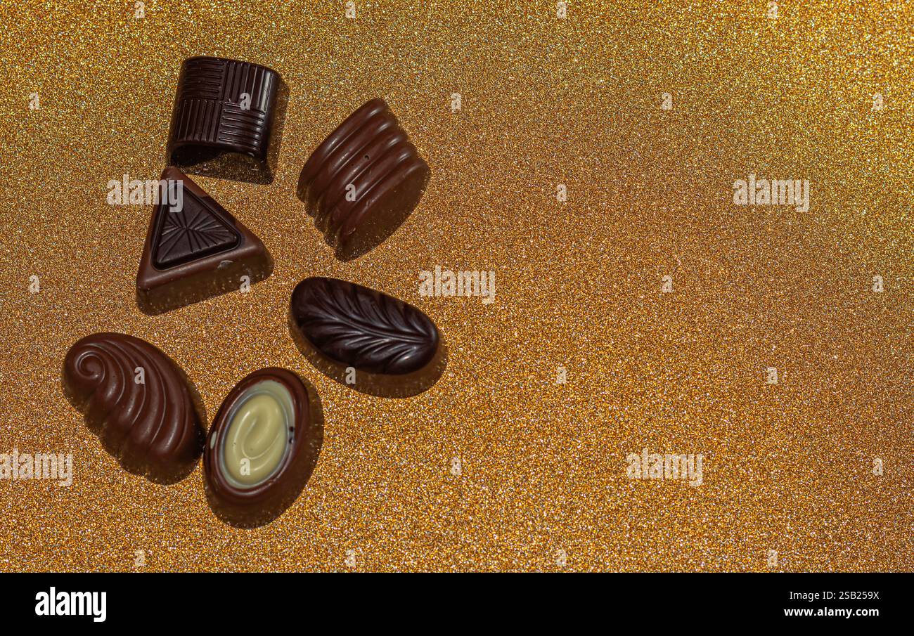 Variety of gourmet chocolates on a sparkling gold background ...
