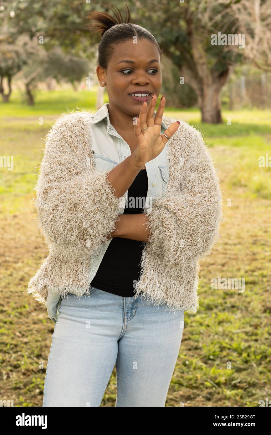 A black woman reacts with surprise, raising her hand in an expressive ...