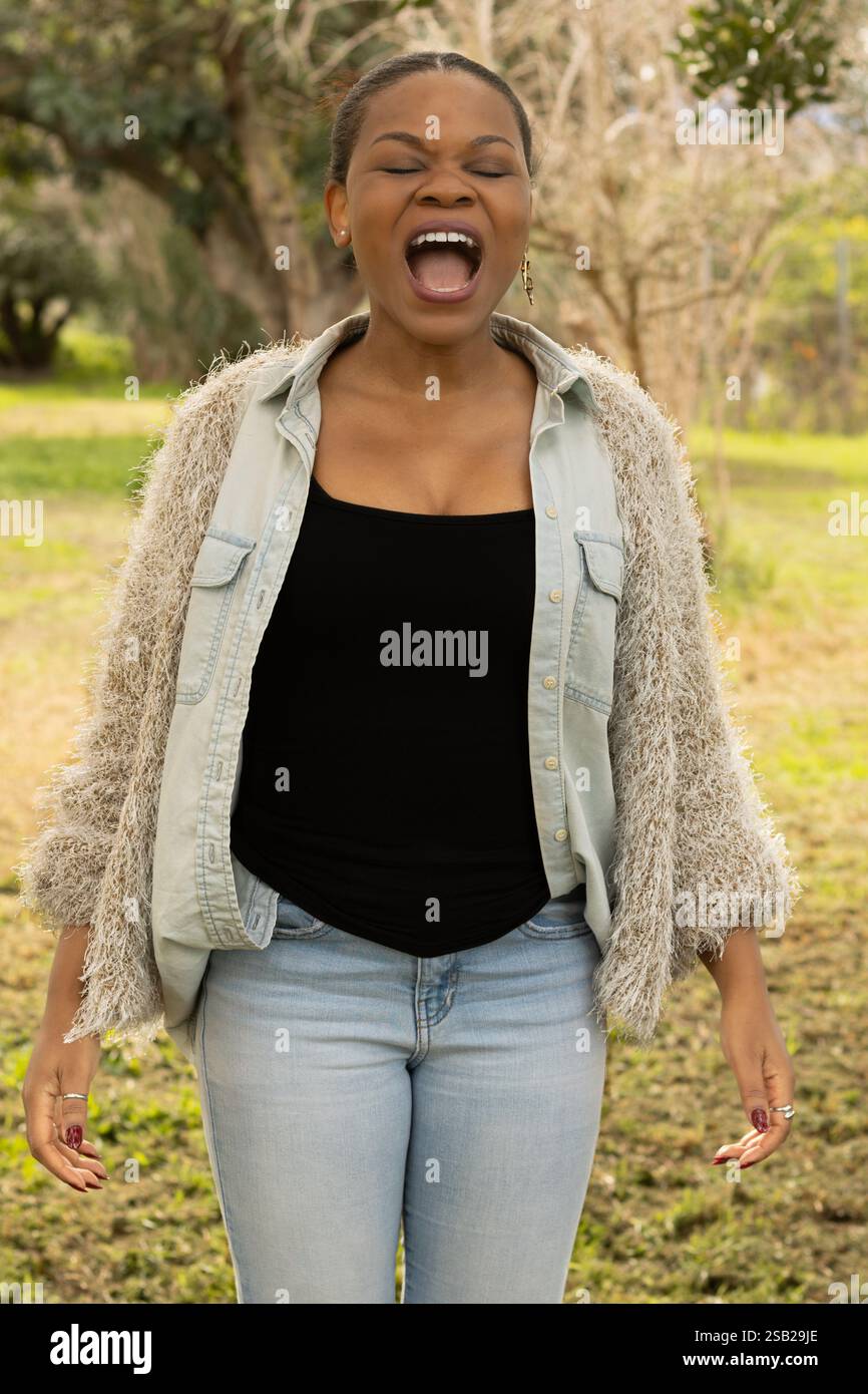 A black woman is standing outdoors with her mouth wide open, expressing ...