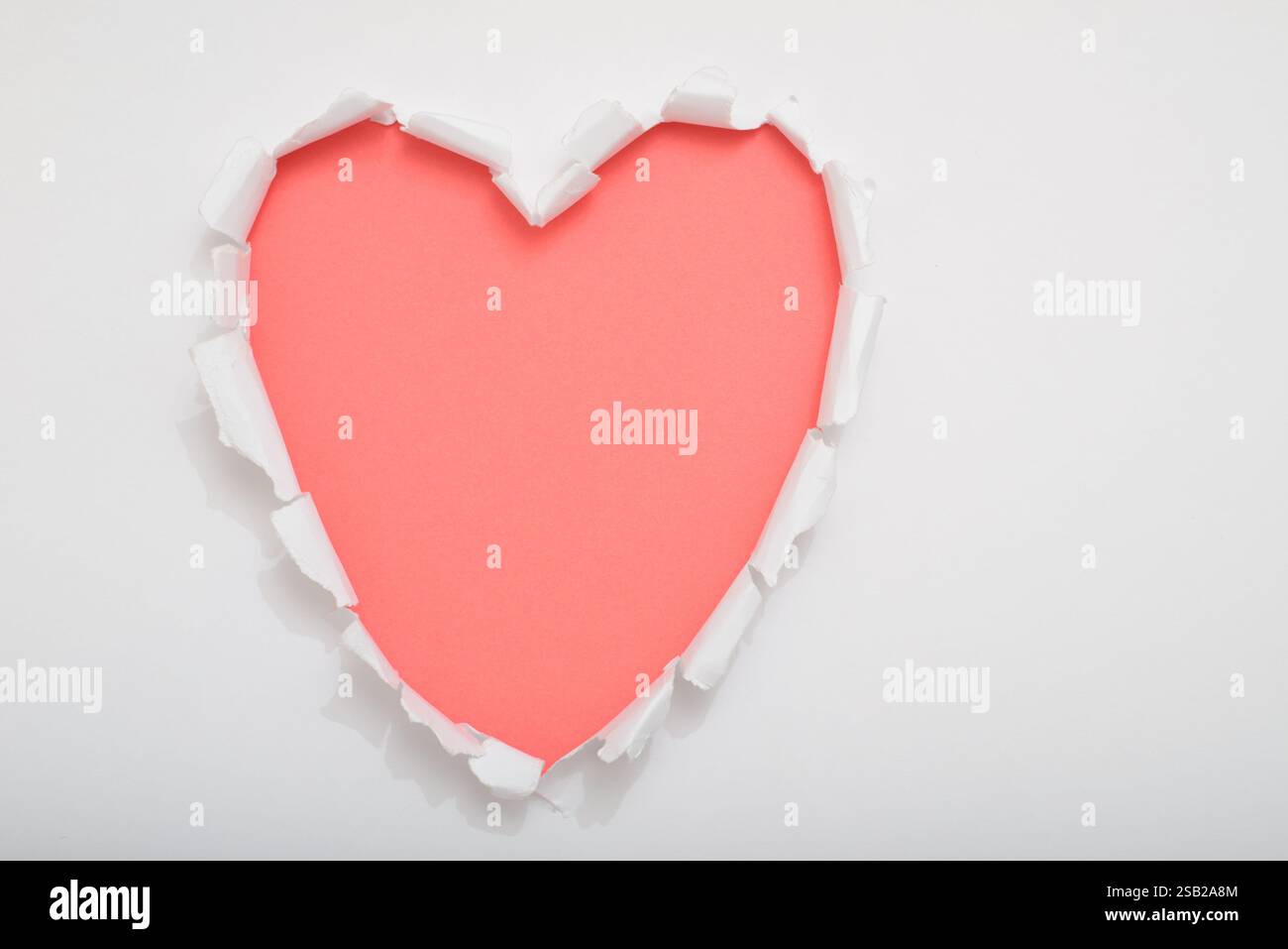 A heart-shaped cutout is formed by tearing white paper to reveal a ...