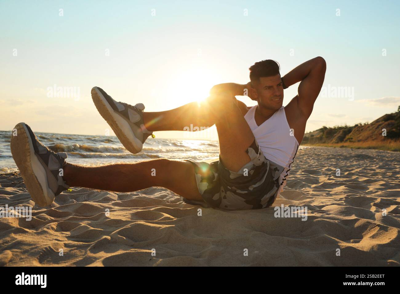 Sporty man with athletic body doing crunches on beach Stock Photo - Alamy