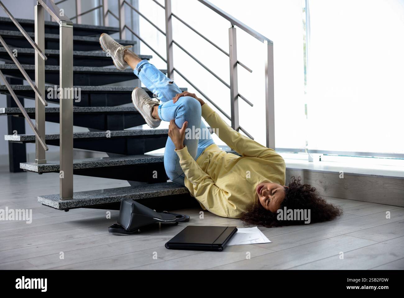 Woman with injured knee on stairs in building after fall. Dangerous ...