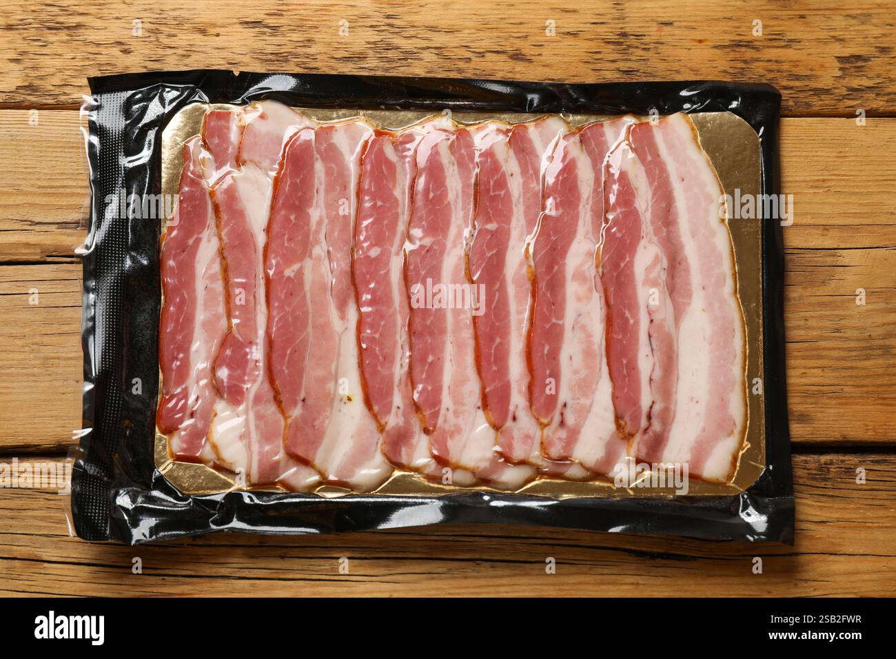 Pack of sliced bacon on wooden table, top view Stock Photo - Alamy