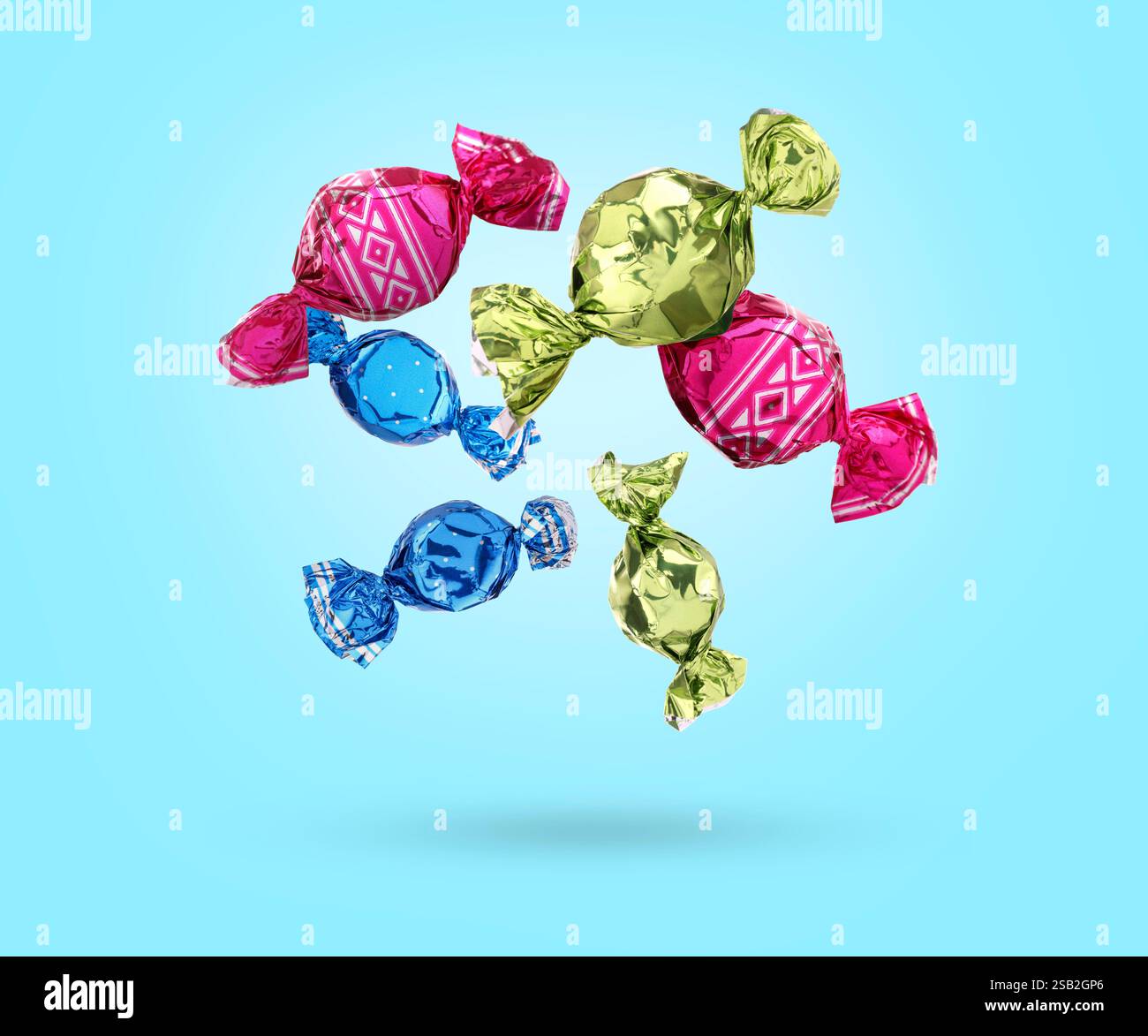 Candies in bright wrappers falling on light blue background Stock Photo ...