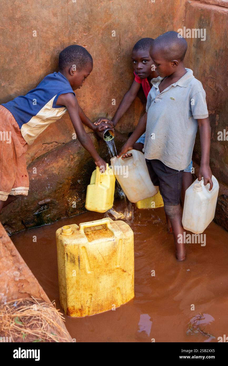 Little boys collecting water into their jerrycans at a nearest source ...