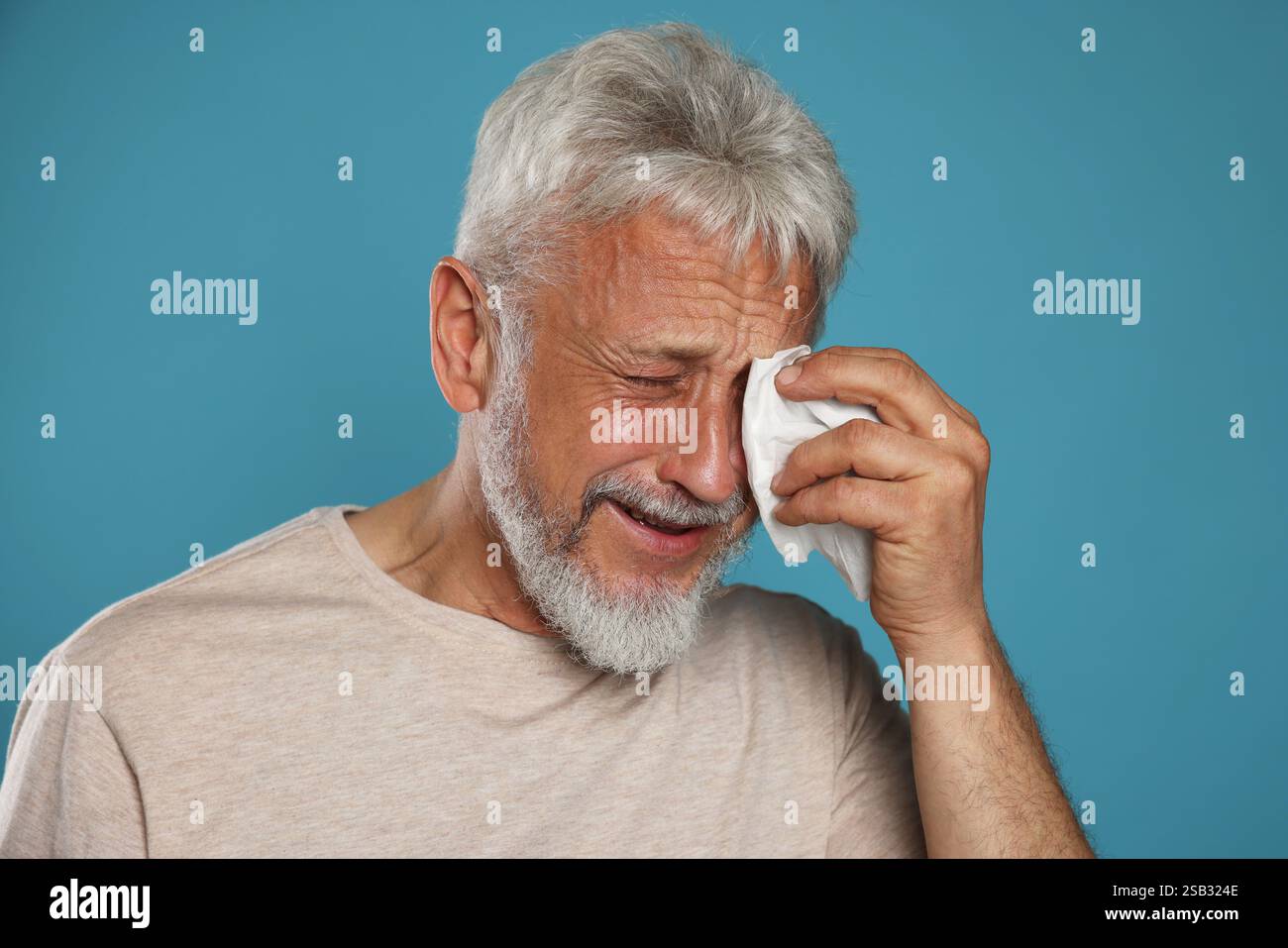 Sad senior man crying on light blue background Stock Photo - Alamy