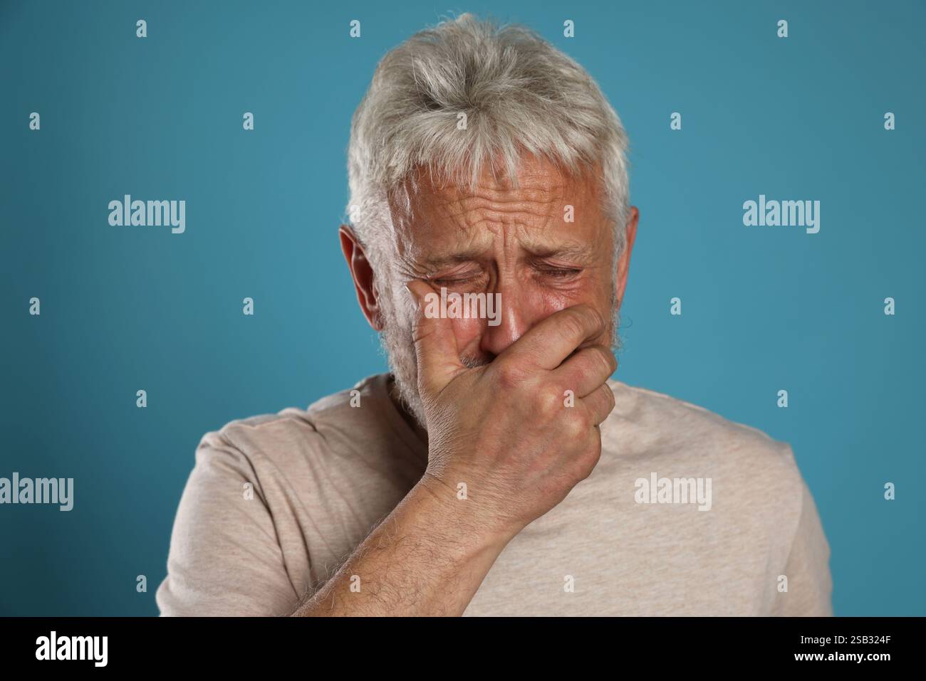 Sad senior man crying on light blue background Stock Photo - Alamy
