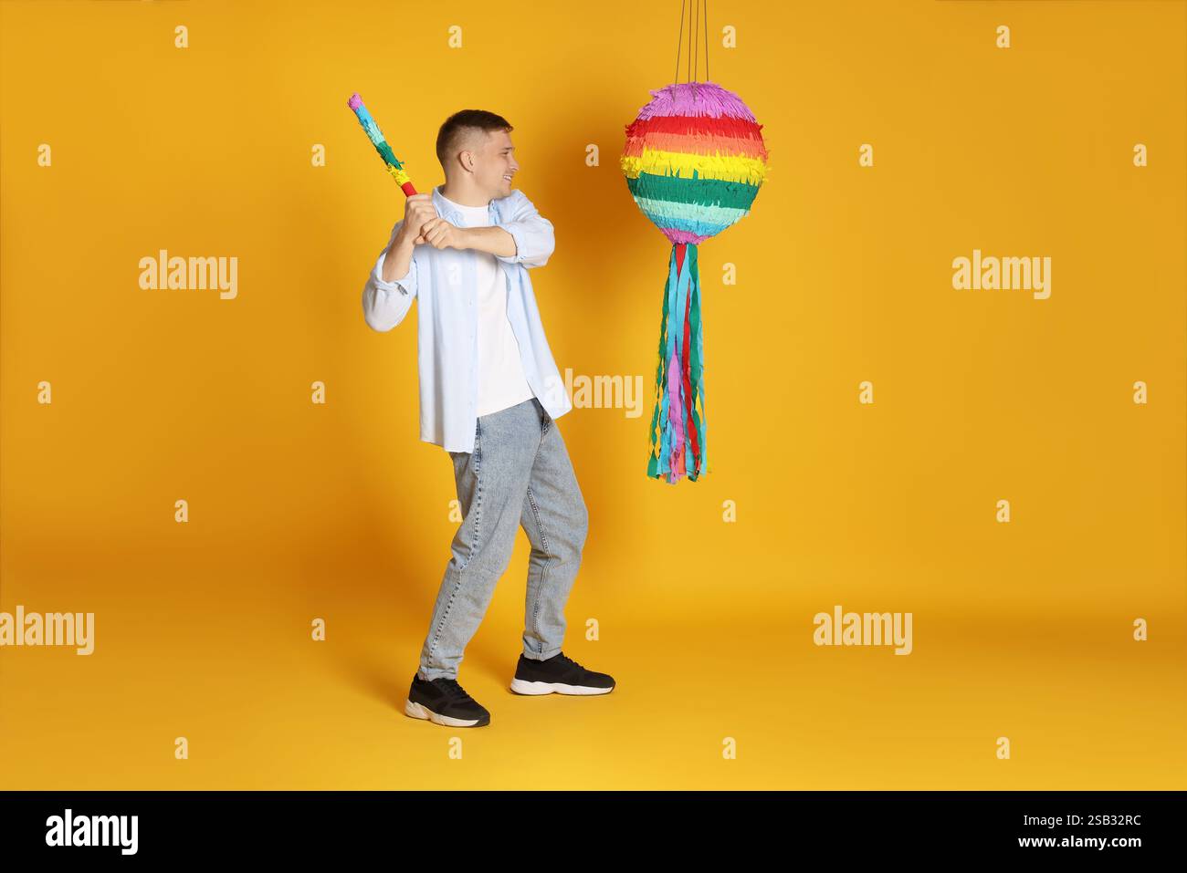Happy man breaking pinata on yellow background Stock Photo - Alamy