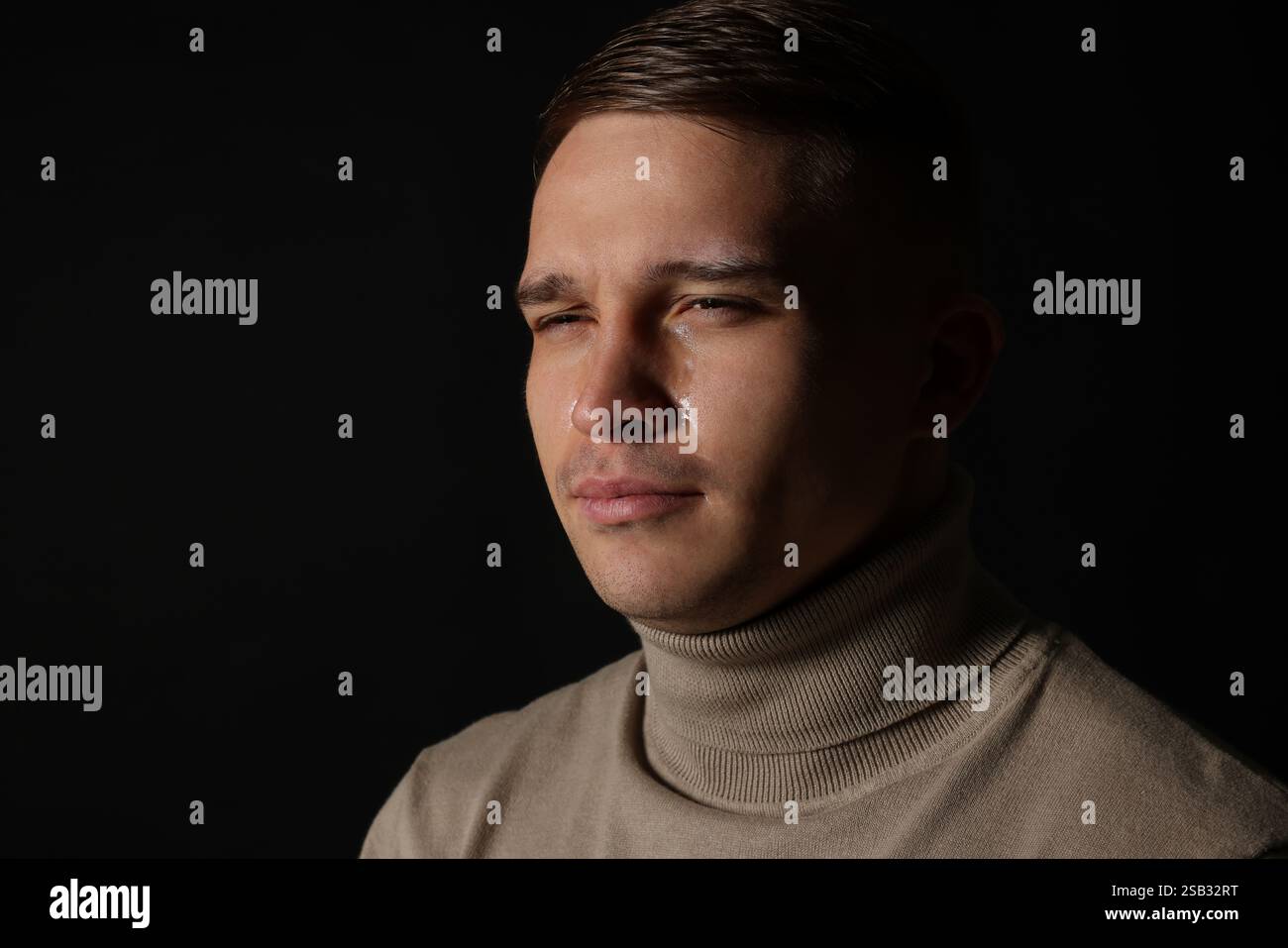 Distressed young man crying on black background Stock Photo - Alamy
