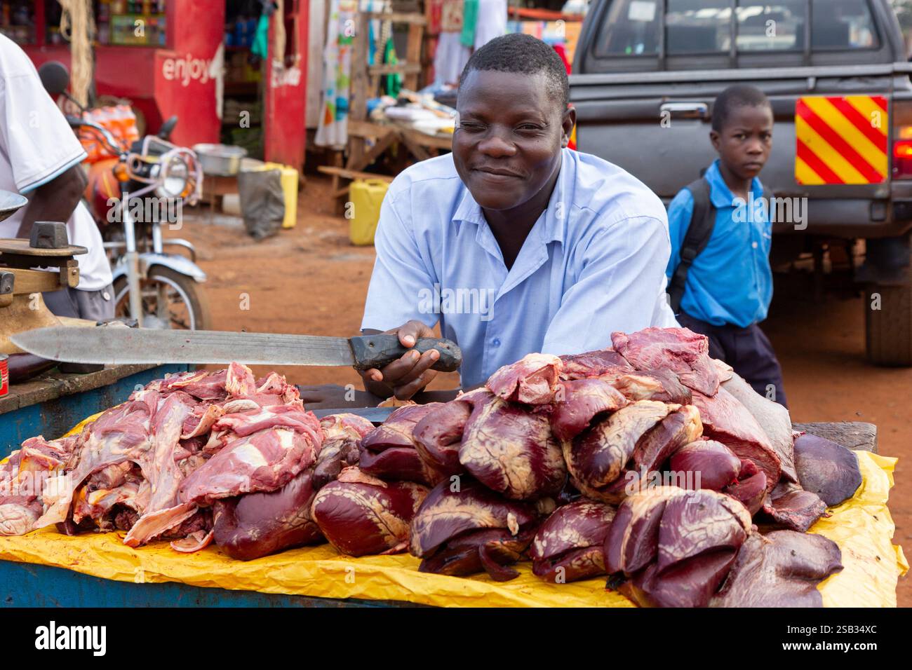 A butcher with fresh meat for sale in a stand in an outdoor market in ...