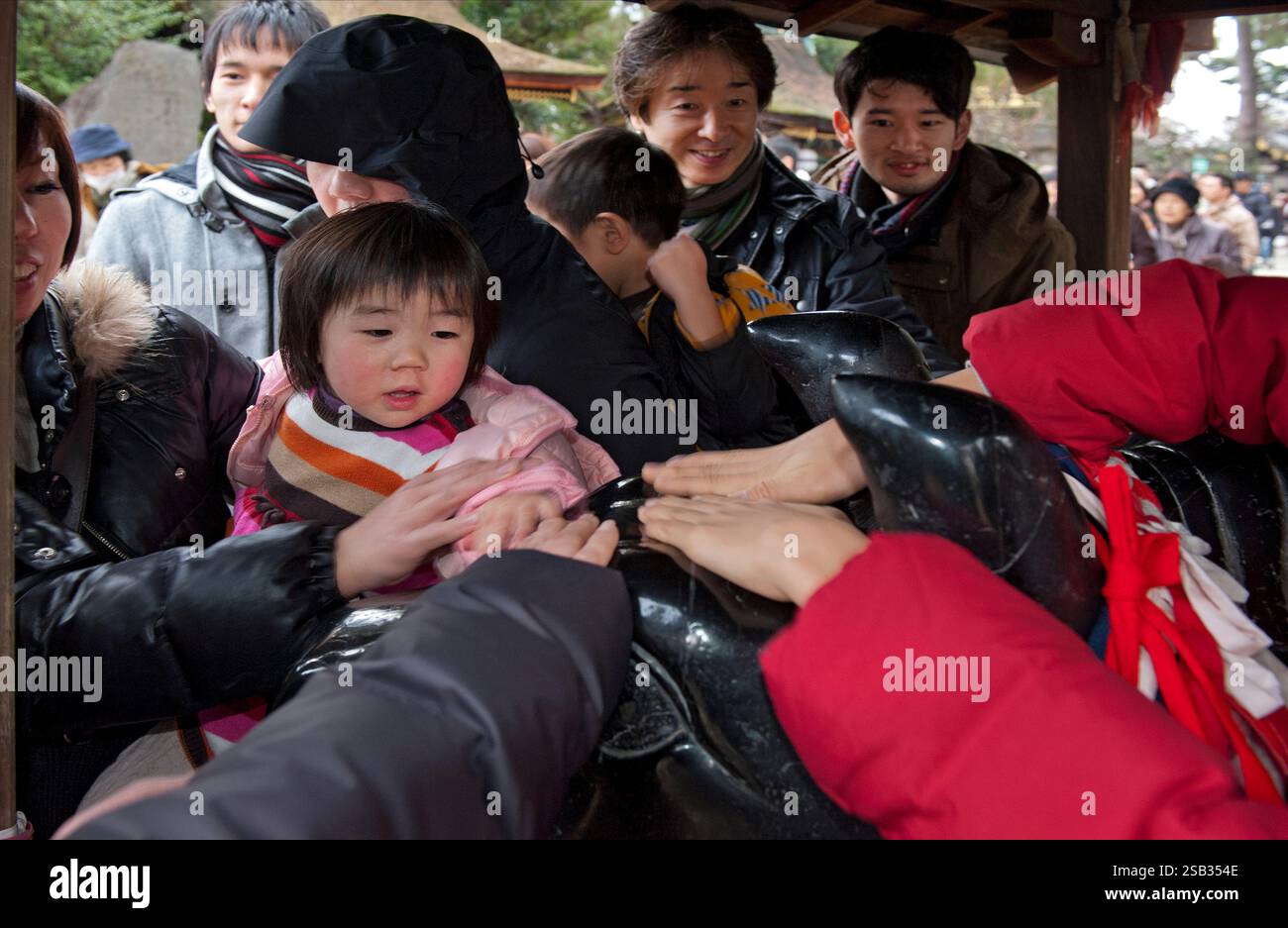 Shrine visitors stroking a sacred cow statue in hopes of alleviating ...