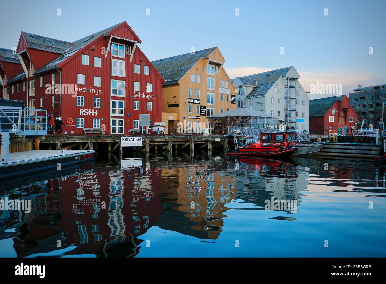 Harbourside buildings in Tromso, Norway, reflect on calm waters at ...