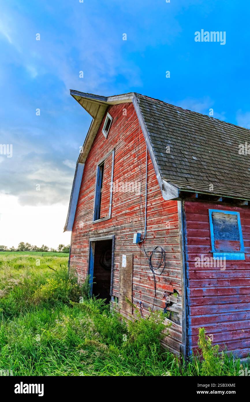 A red barn with a blue window. The barn is old and has a lot of rust ...