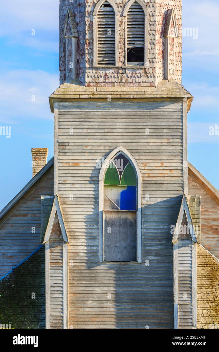 A church steeple with a stained glass window. The window is blue and ...