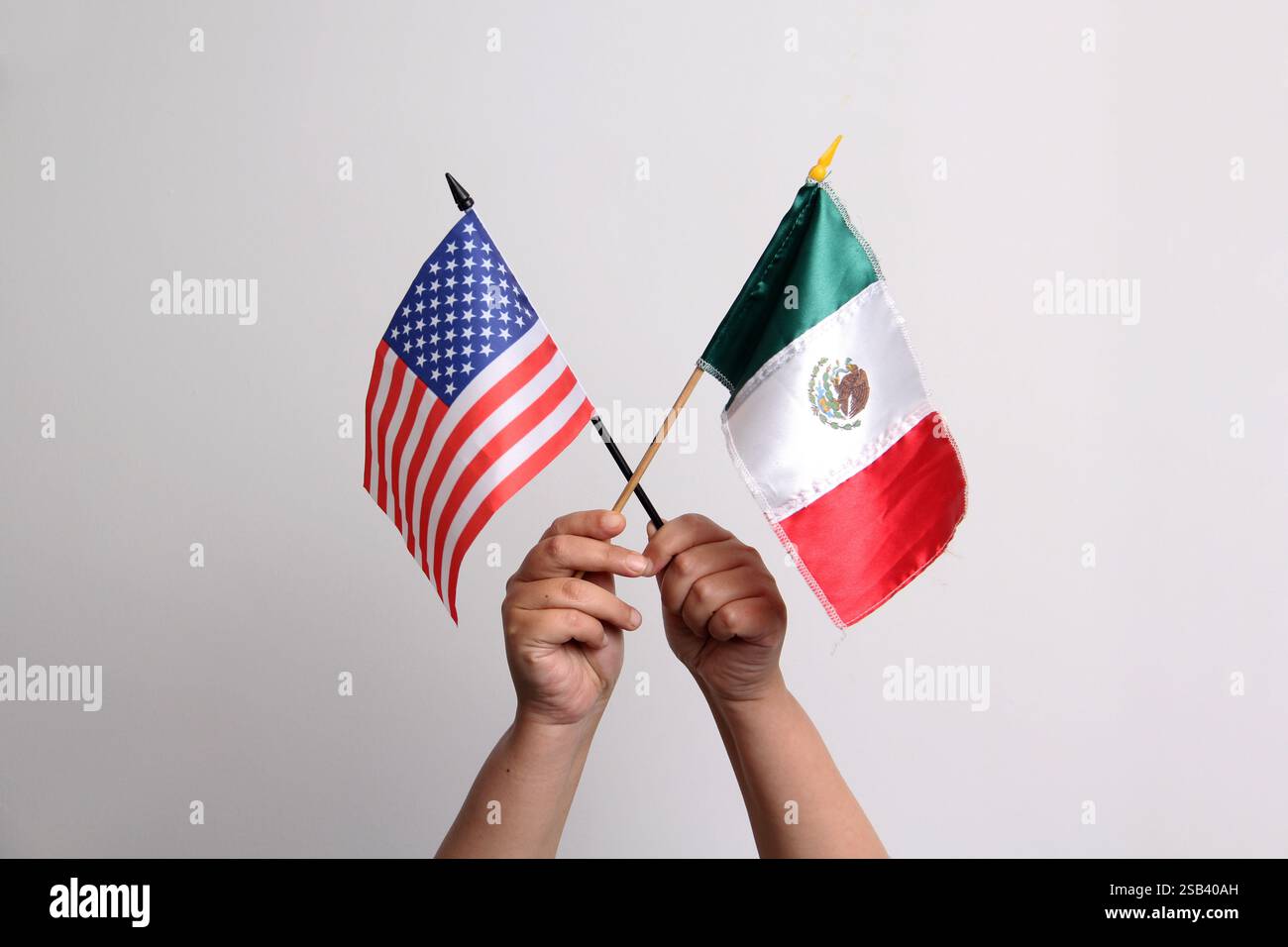 Hands holding flags of Mexico and the United States as a representation ...
