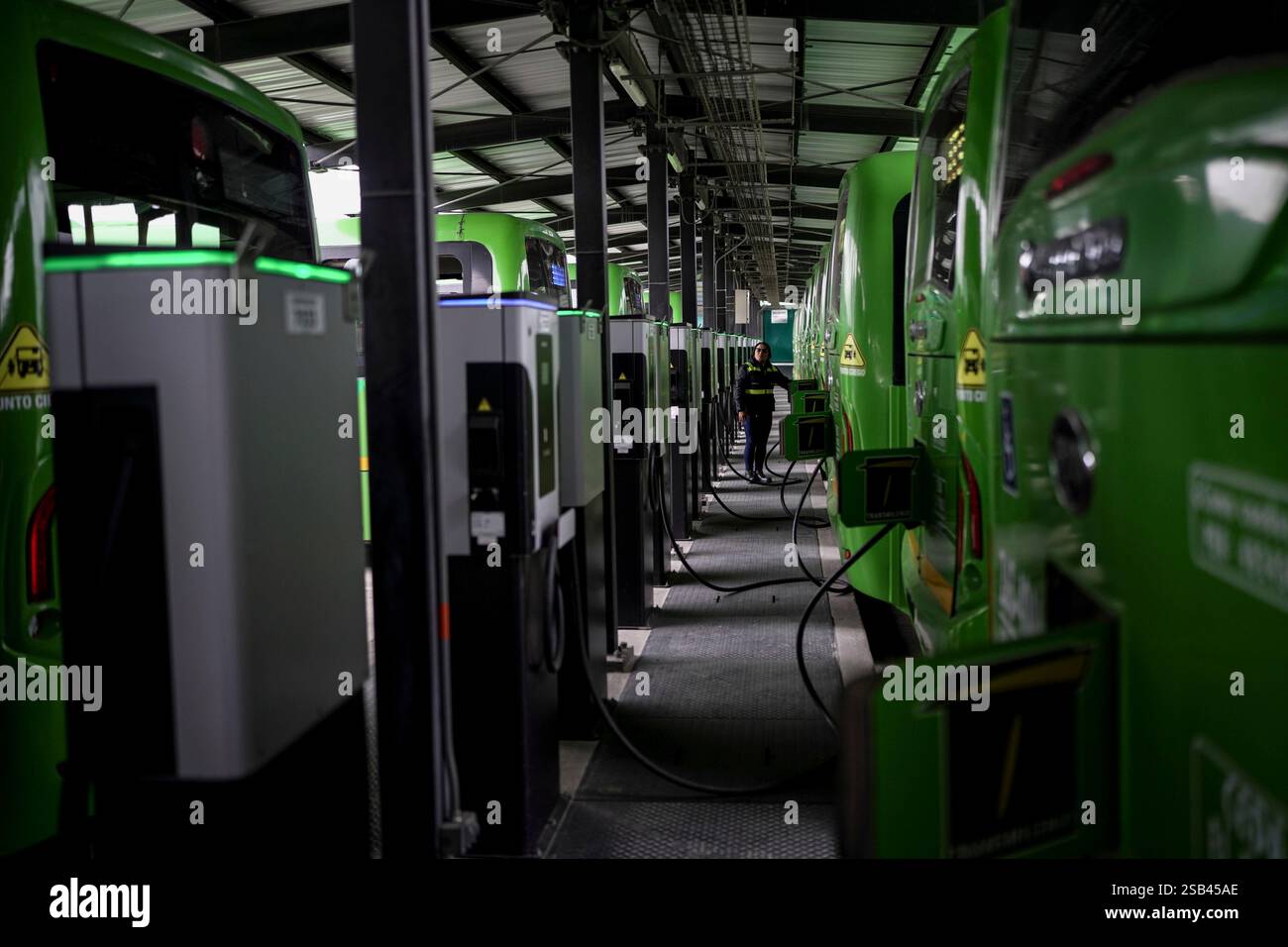 A worker charges the battery of one the electric buses of the company ...