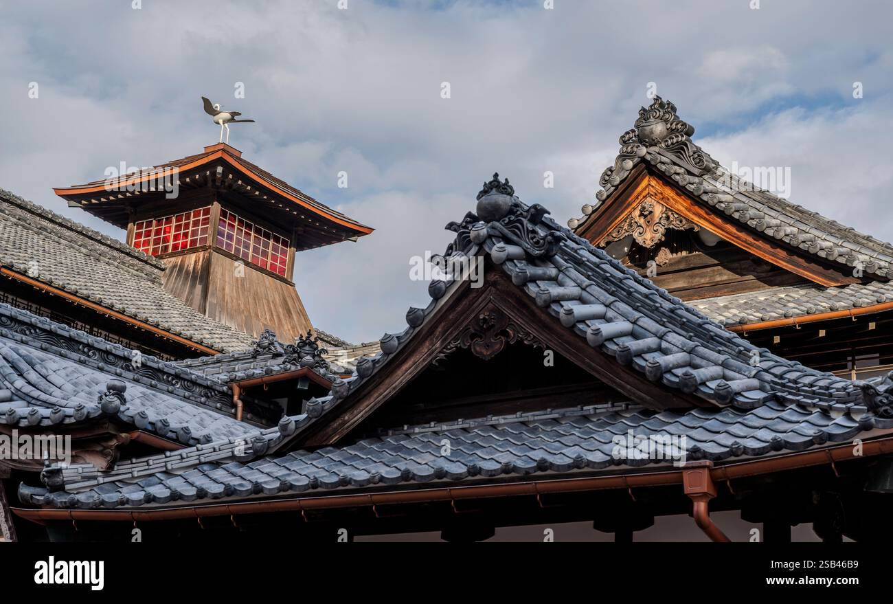 Roof peaks and an egret statue at Dogo Onsen Honkan, a public bath ...