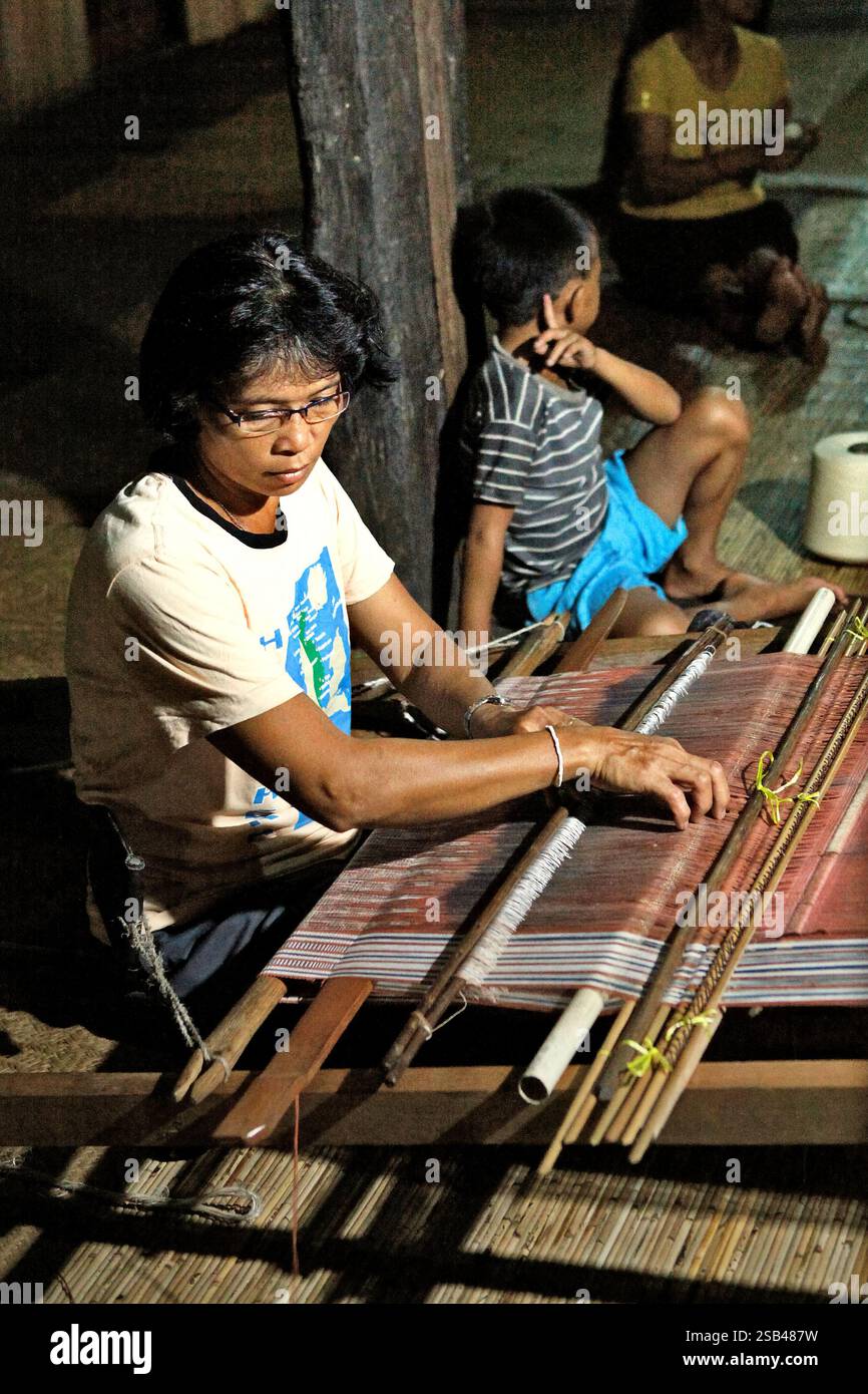 A woman weaving a traditional woven fabric at the longhouse of ...