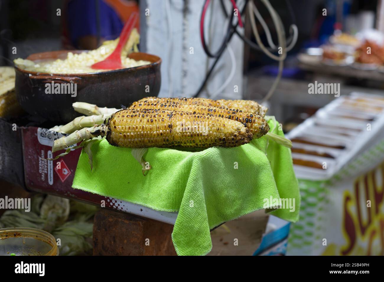 Elote roasted on charcoal at a street food stall in Mexico. Roasted ...