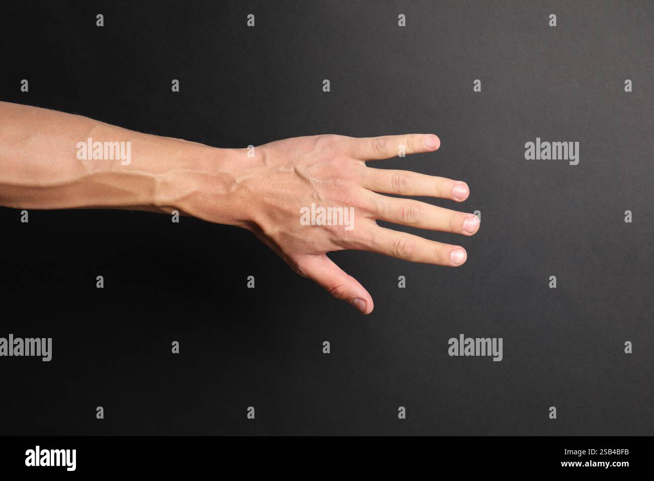Man with bulging veins on his arm against black background, closeup ...