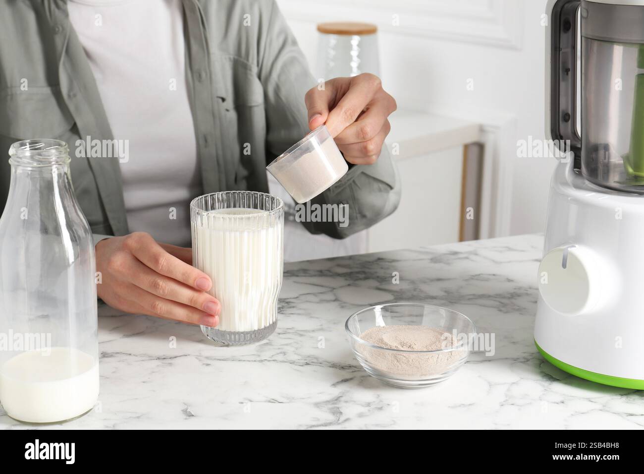 Making protein cocktail. Woman adding powder into glass with milk at ...