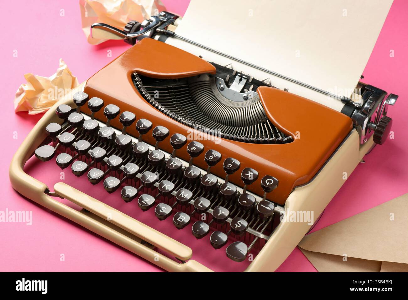 Vintage typewriter, crumpled paper and envelope on pink background ...