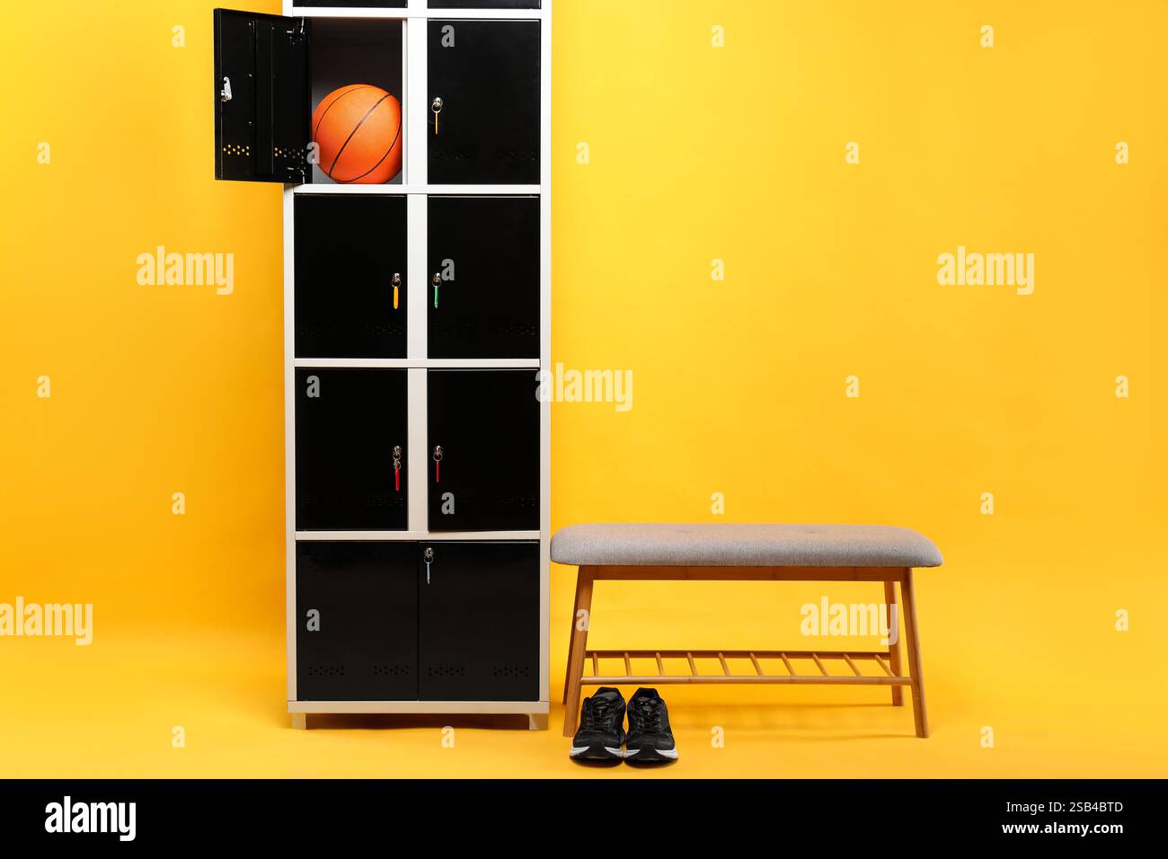 Open locker with basketball ball, bench and sneakers on orange ...