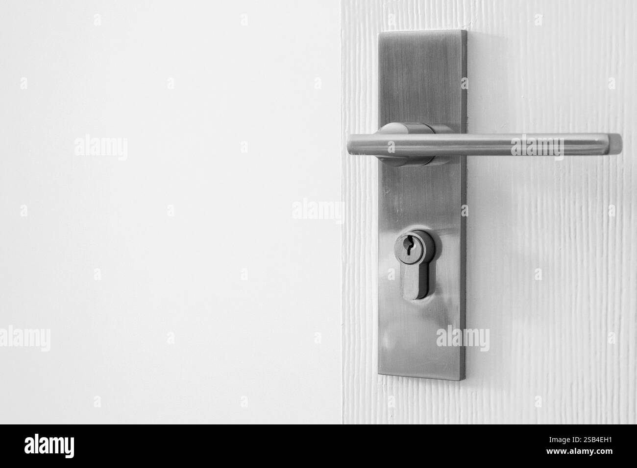 Modern door handle with keyhole on white door Stock Photo - Alamy