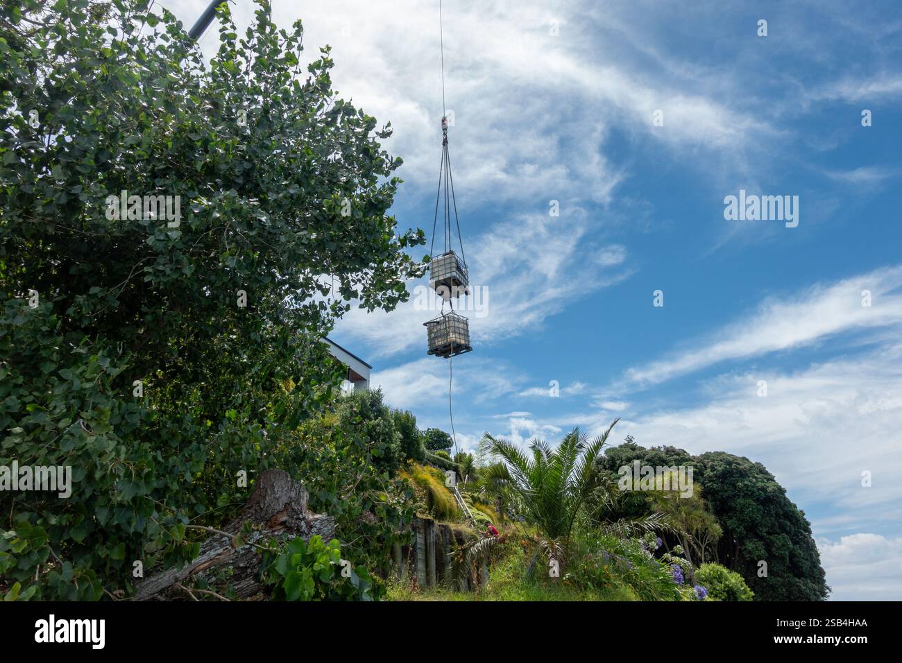 Low point of view of crane lifting load high into sky. over trees and ...