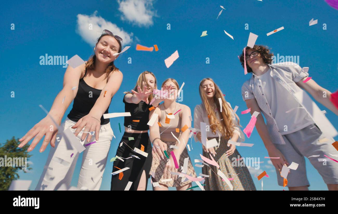 Group of five exuberant high school students joyfully tossing vibrant ...