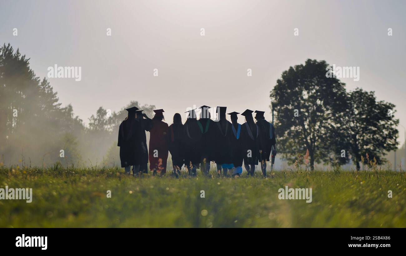 Graduates walking together in a sunlit field, celebrating their ...