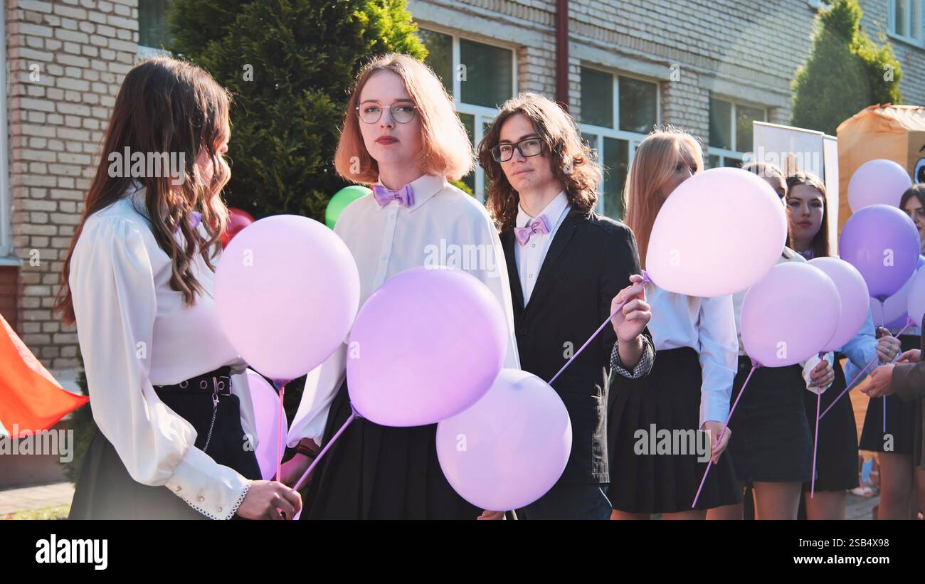 Group of elegant students holding purple balloons on their first school ...