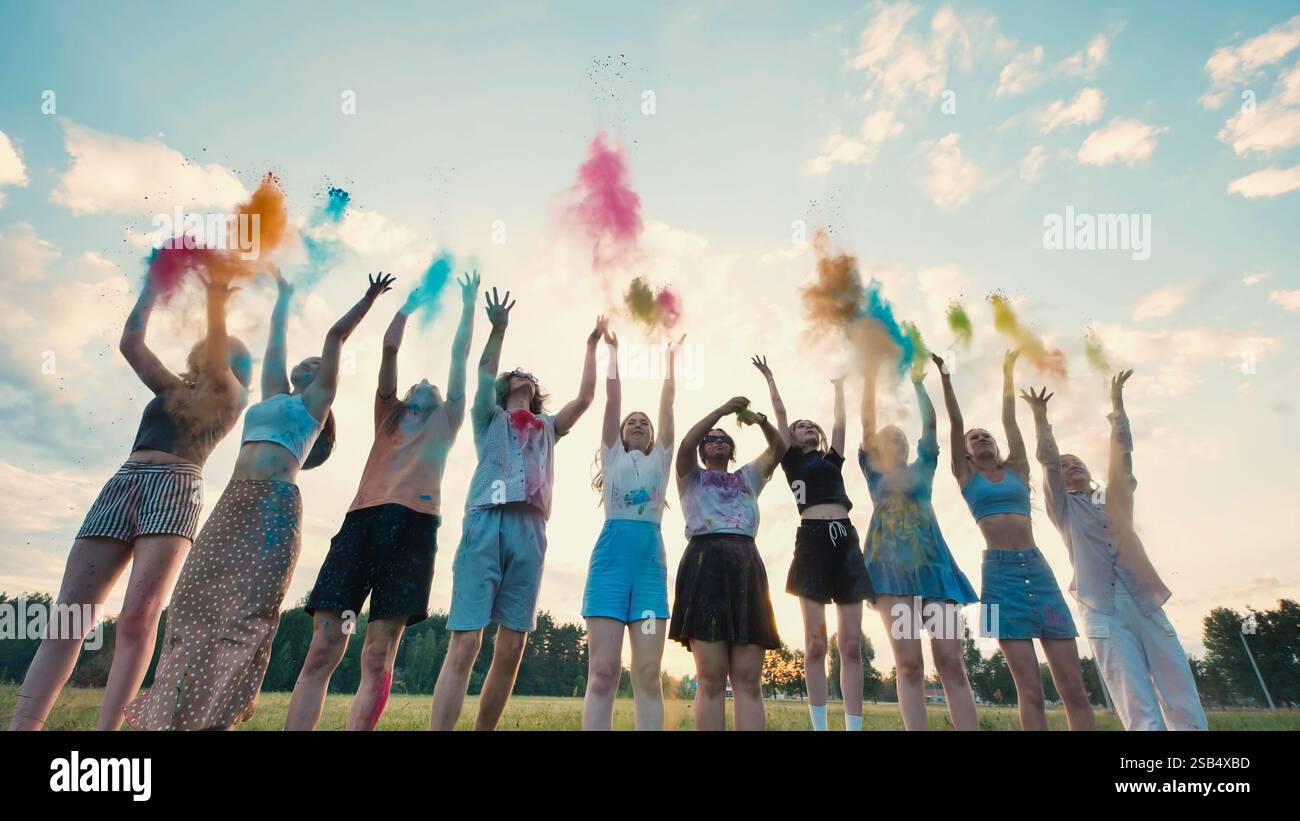 Group of young students throwing colorful holi powder in the air ...