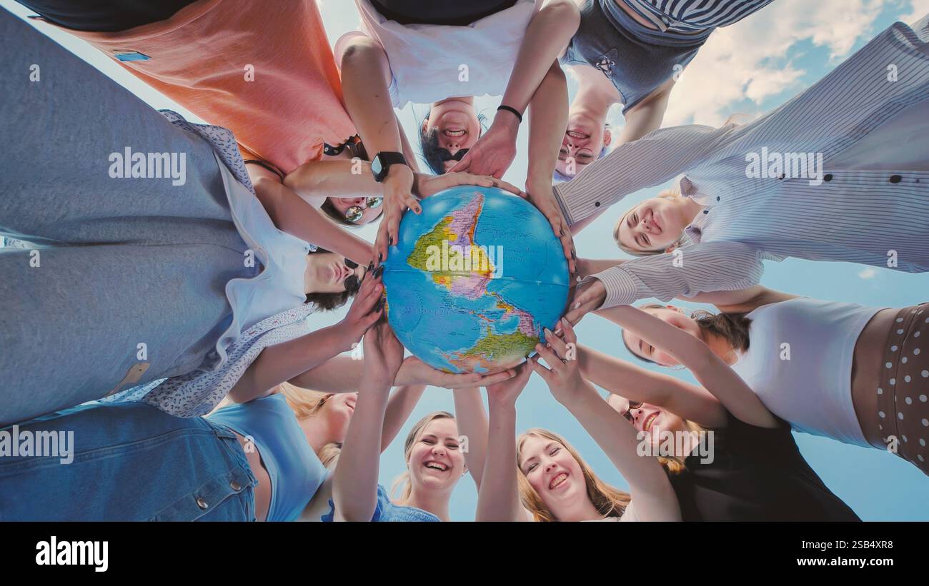 Group of smiling students holding a globe, promoting global citizenship ...