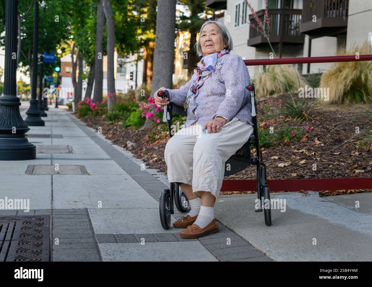 Elderly woman sitting on a mobility walker outside the retirement ...