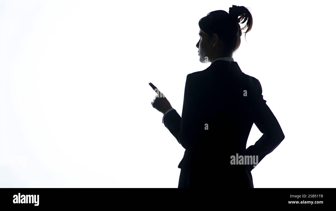 A silhouetted businesswoman stands confidently in a bright, empty space ...