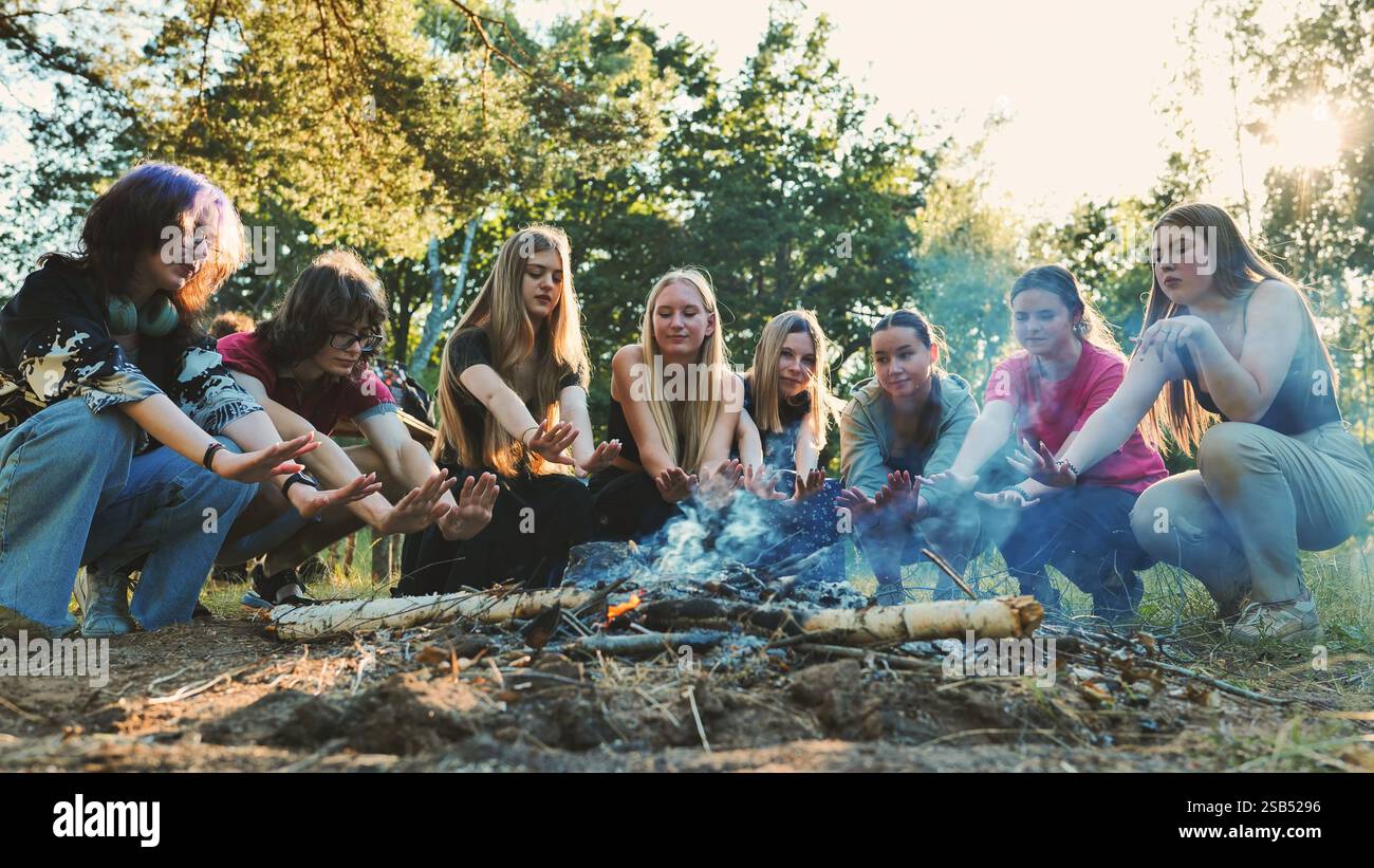 Group of female students are warming their hands by a campfire in the ...