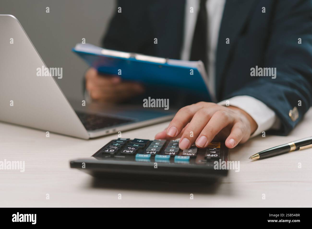 A businessman at his workplace uses a laptop and paper to manage ...