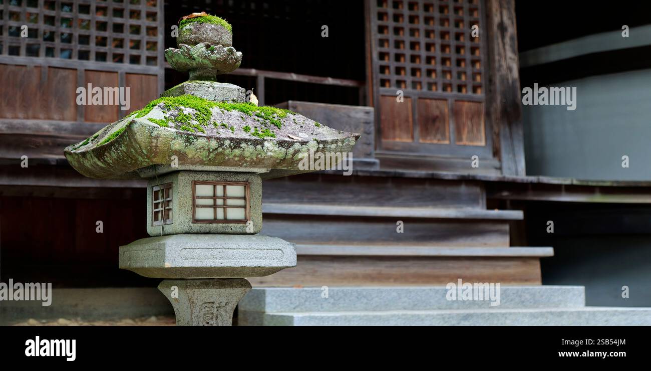 Traditional japanese stone lantern with moss in front of temple Stock ...