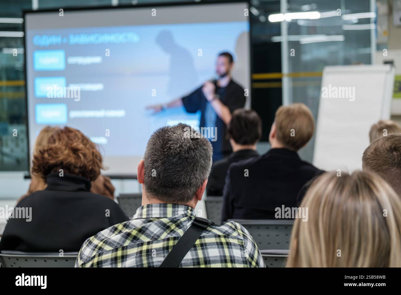 Attendees listen to a professional speaker presenting information on a ...